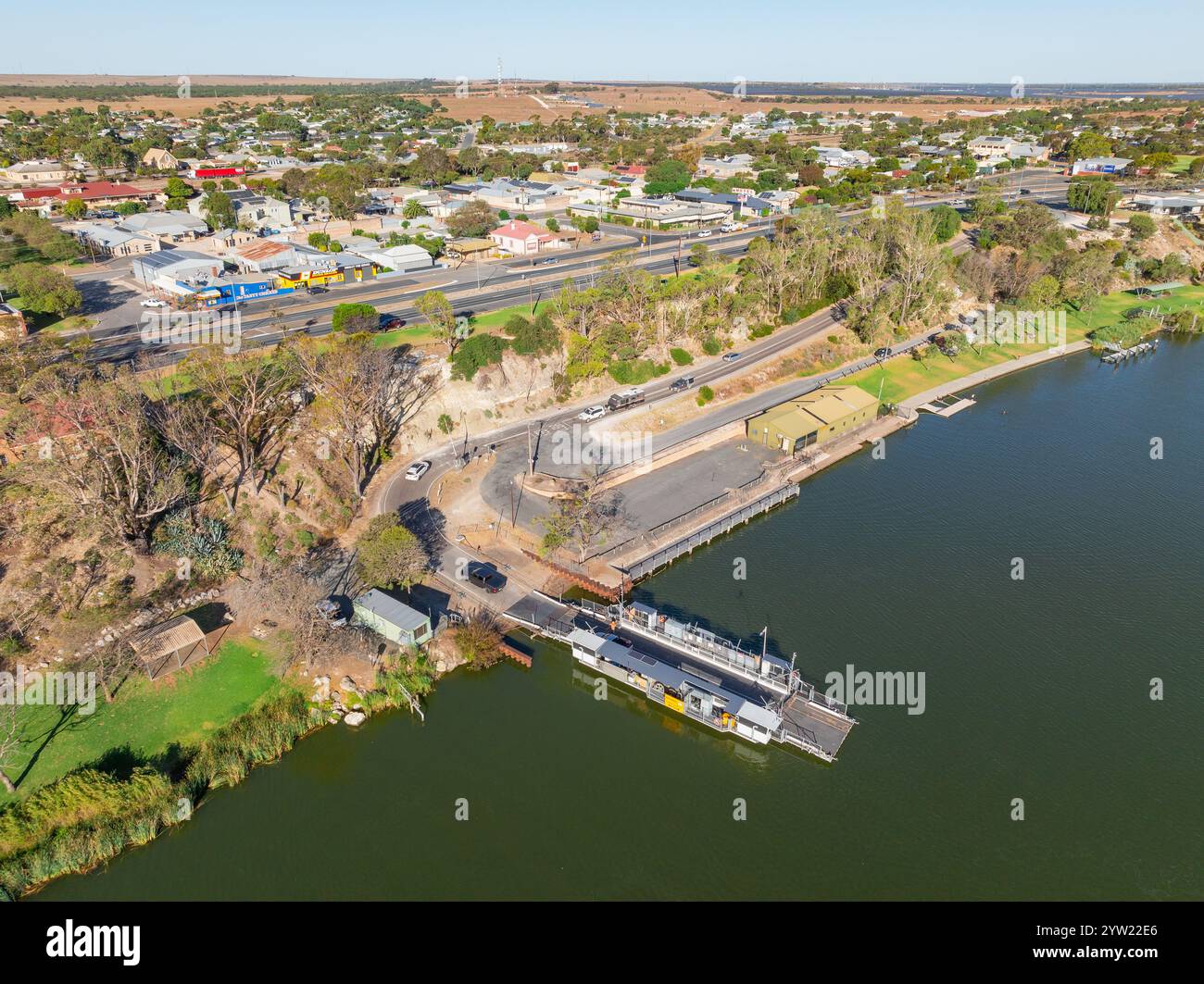 Aerial view of a car ferry docked at the side of a river below a rural ...