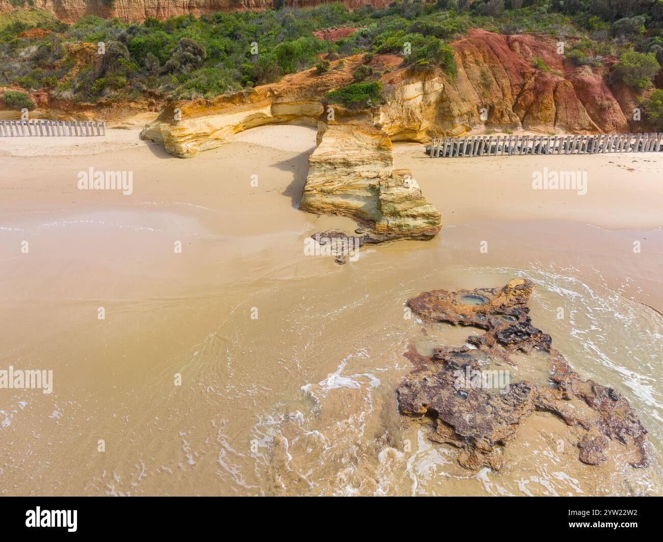 Aerial view of jagged rocks on a wide sandy beach at Point Roadknight ...