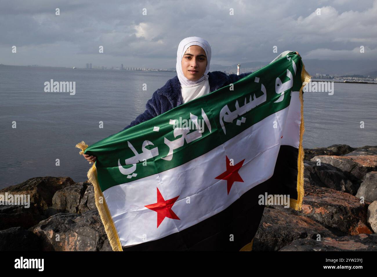 A Syrian woman poses with a Syrian National Army flag. The fall of ...