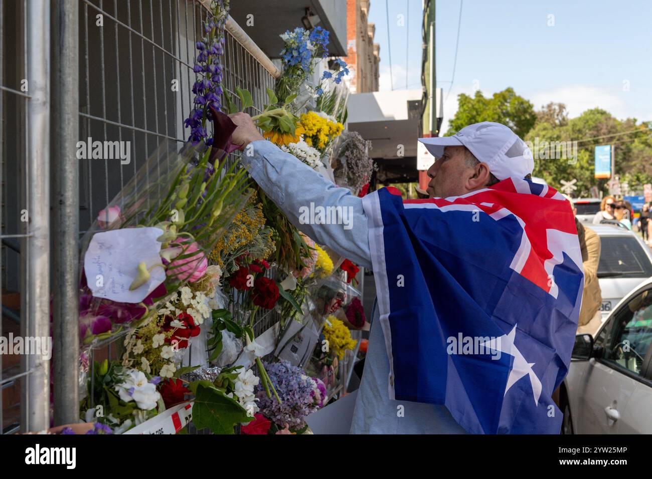 A man wrapped in an Australian flag places flowers in the temporary ...