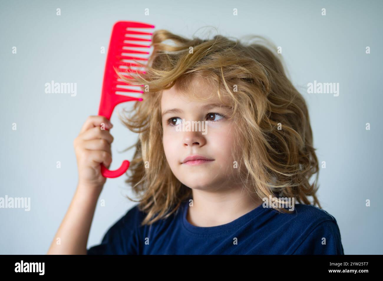 Daily hair care routine. Child with tangled blonde long hair tries to ...