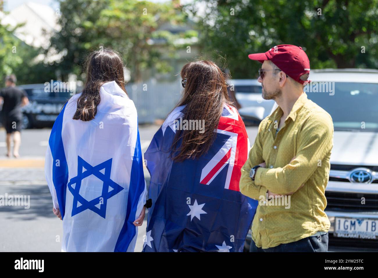 Two women wrapped in Israeli and Australian flags walk away after ...