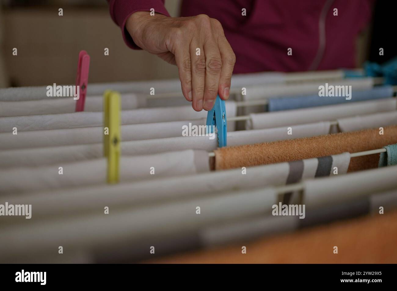 Woman hand holding clothespin and hanging clean laundry on drying rack ...