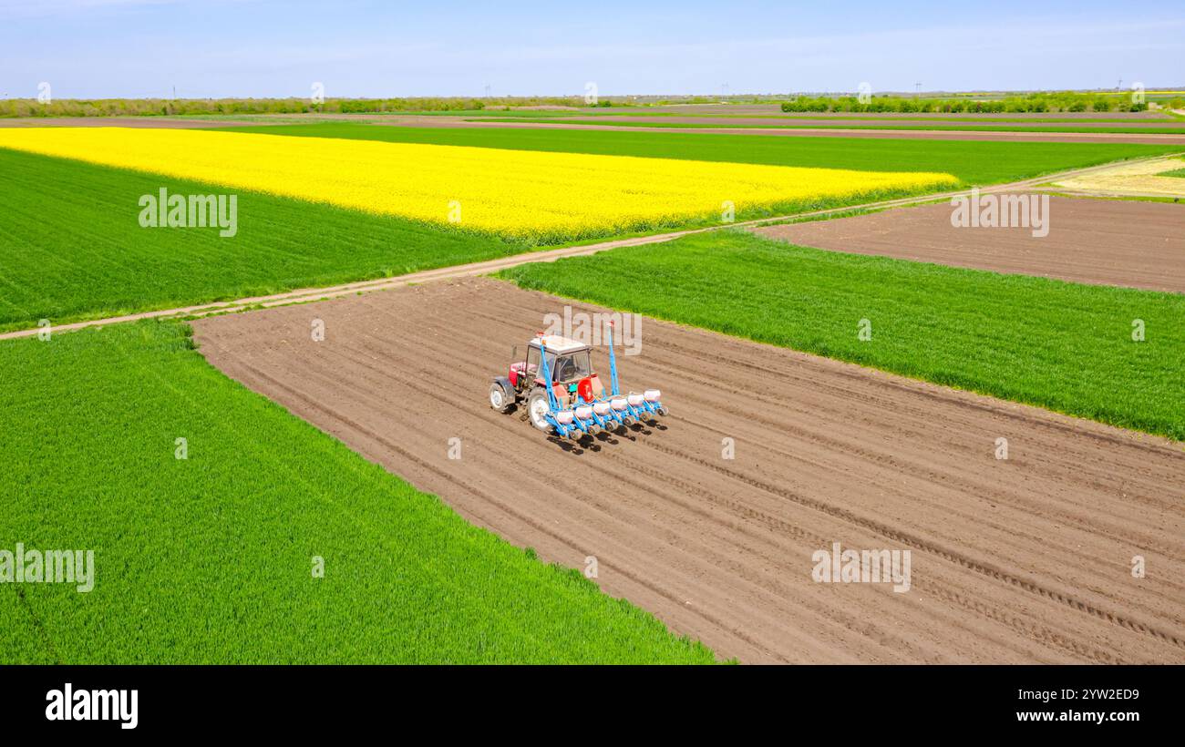 Above view, of tractor as pulling mechanical seeder machine over arable ...