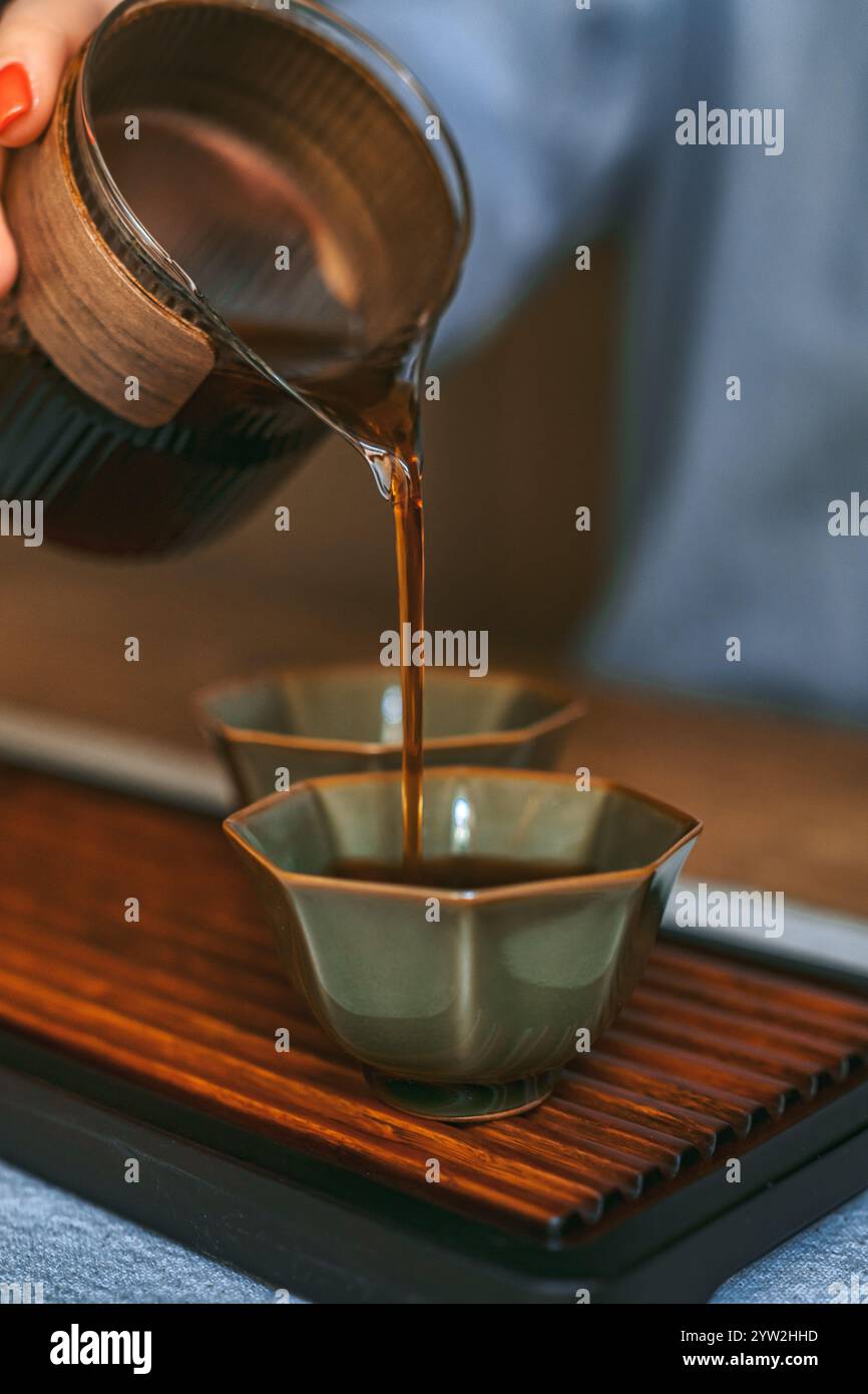 A serene moment of pouring aromatic tea into delicate cups, symbolizing ...