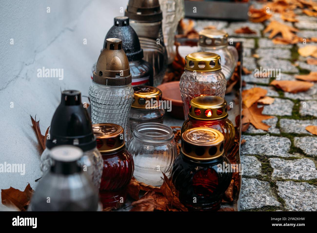Row of remembrance candles with autumn leaves on a cobblestone path ...