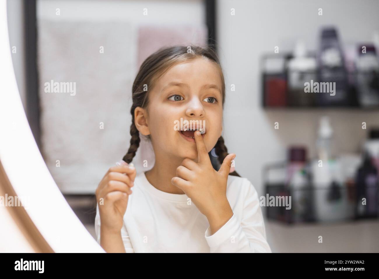 Portrait of young Caucasian girl holding fallen tooth in bathroom while ...