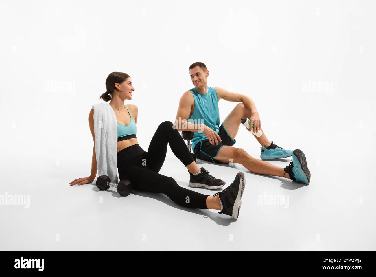 Young smiling man and woman sitting on floor, drinking water and ...