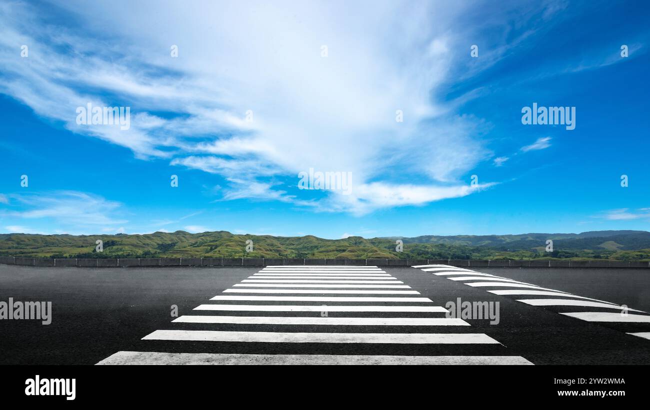 Asphalt street with pedestrian crosswalk and mountain range with blue ...