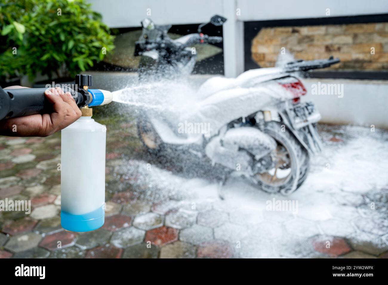 Professional worker hand washing the motorcycle with cleaning foam ...