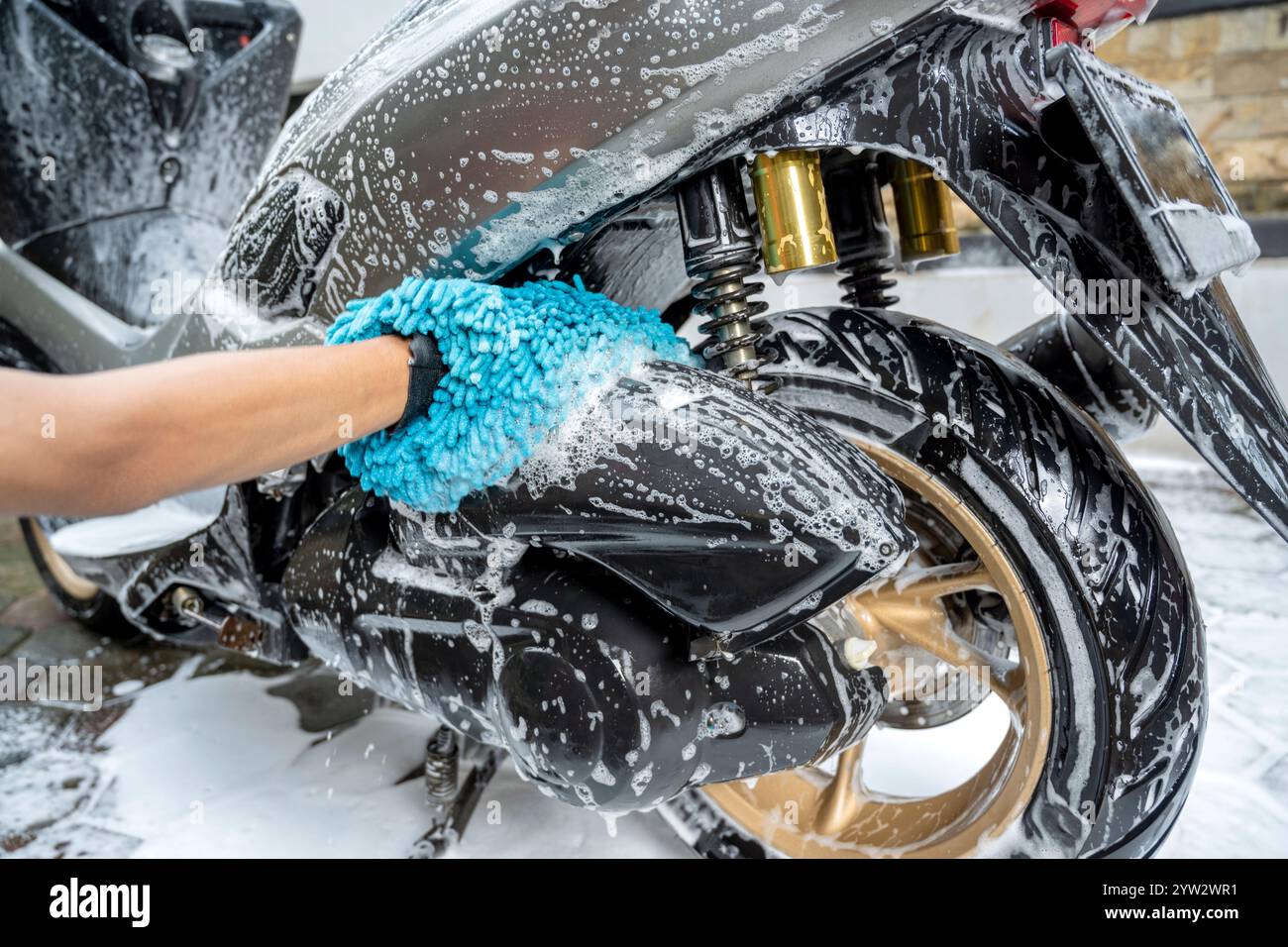 Professional worker hand washing the motorcycle with cleaning foam ...
