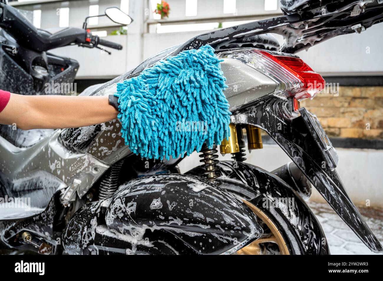 Professional worker hand washing the motorcycle with cleaning foam ...
