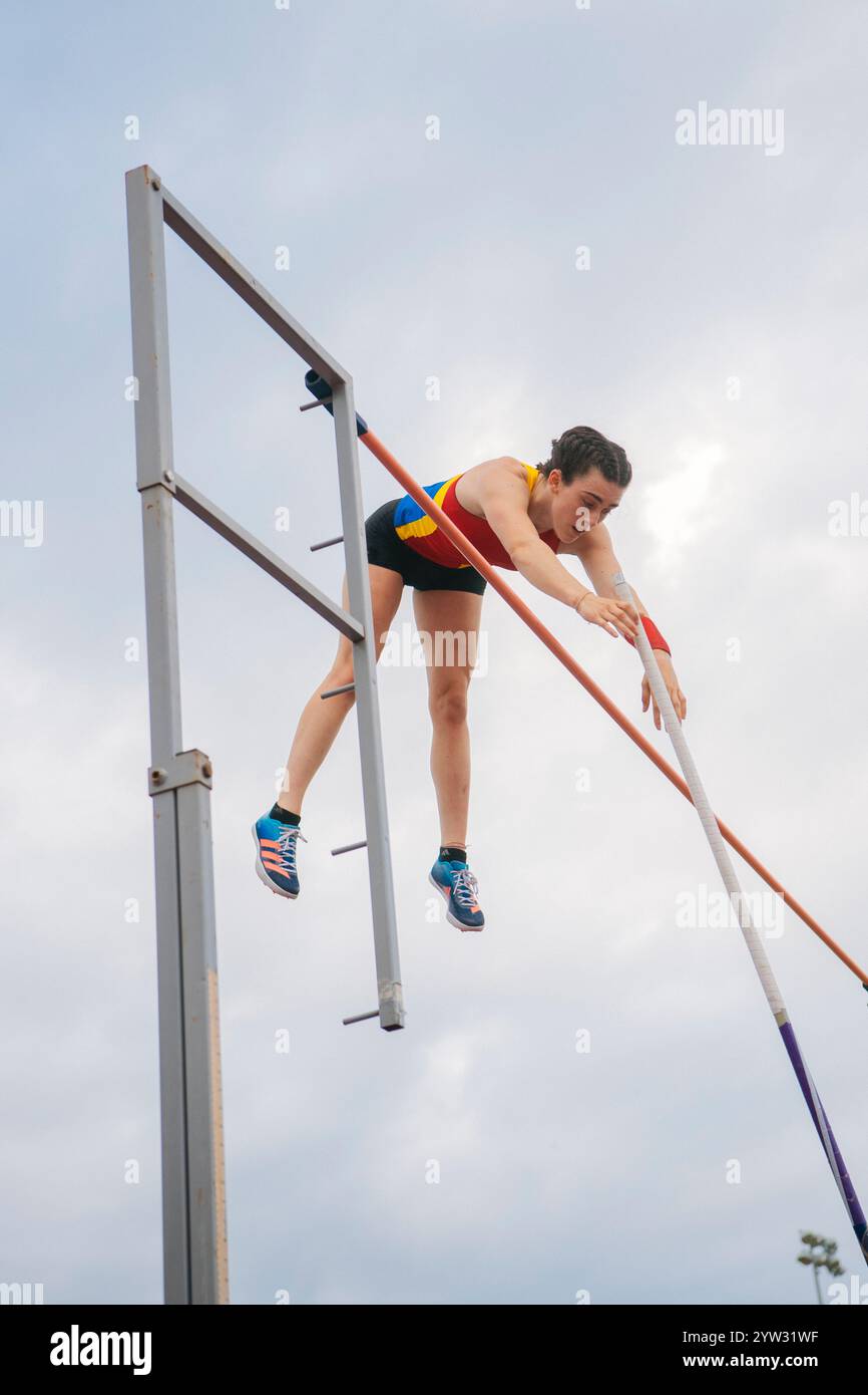 Female athlete in midair attempting a high jump over the bar at an ...