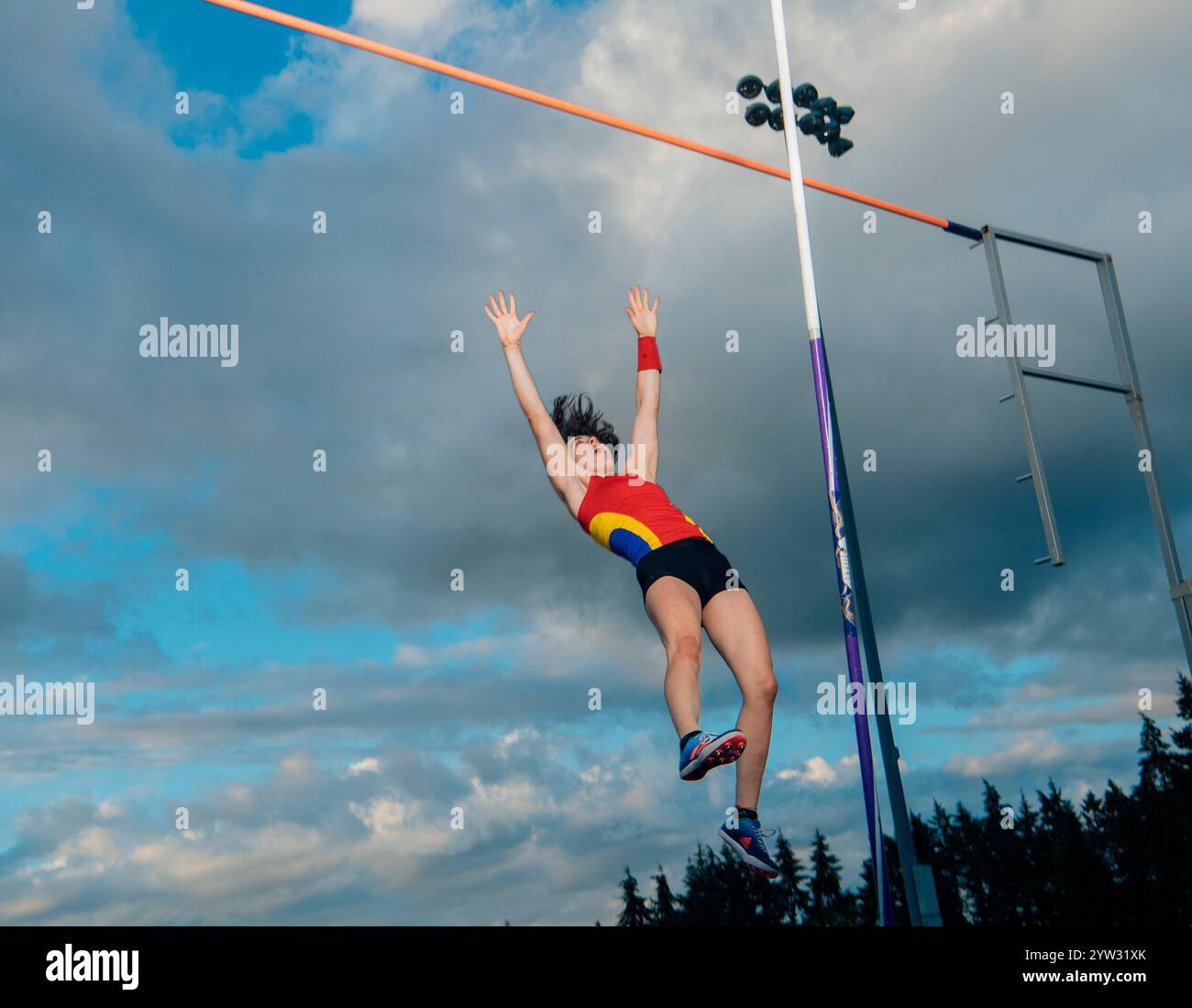 Female athlete in midair while attempting a high jump at a track and ...