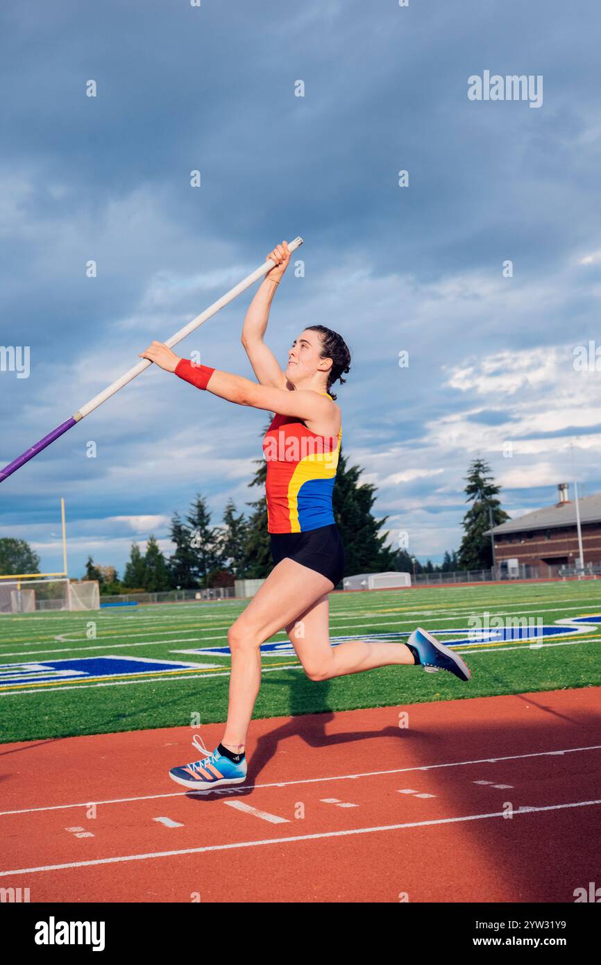 Female pole vaulter in mid-action on a sunny day at an athletic track ...