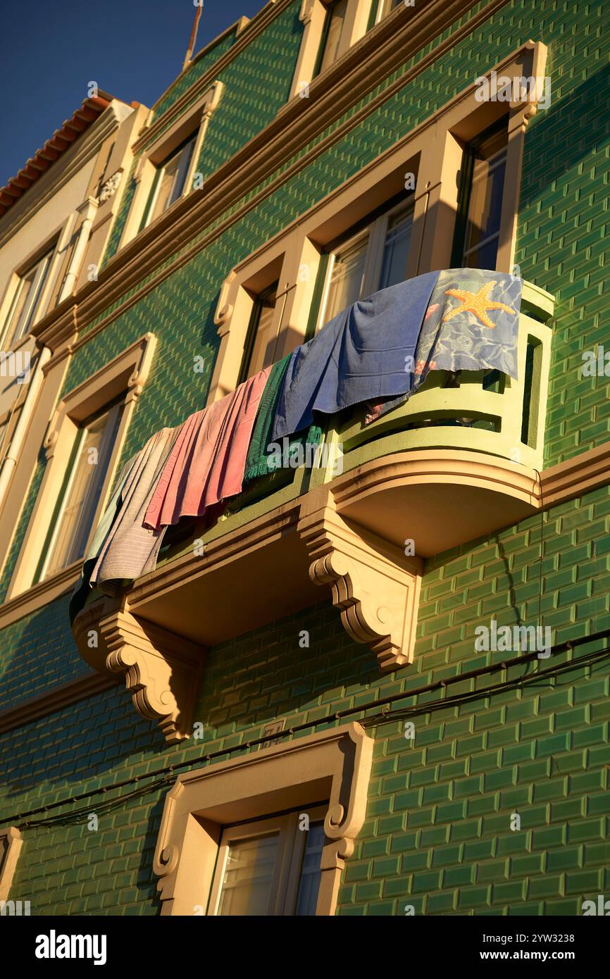 Colorful laundry hangs to dry on the balcony of a green tiled building ...