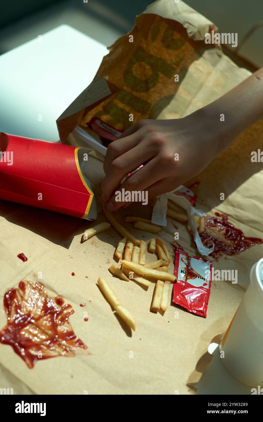 Teenager's hands are shown grabbing fries from a fast food meal with ...