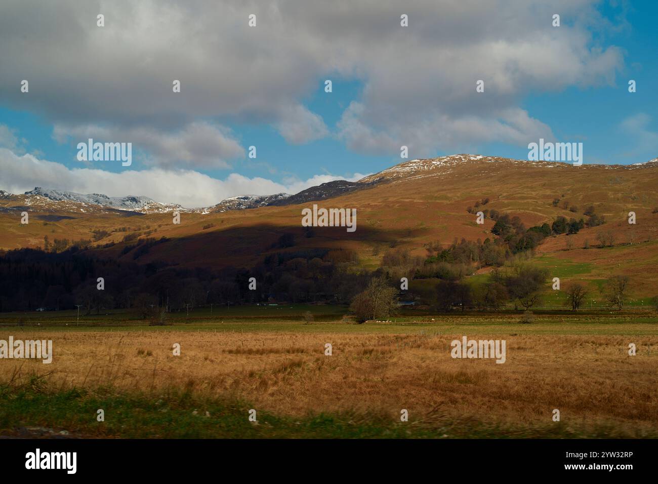 Scenic view of rolling hills with patches of snow under a cloudy blue ...