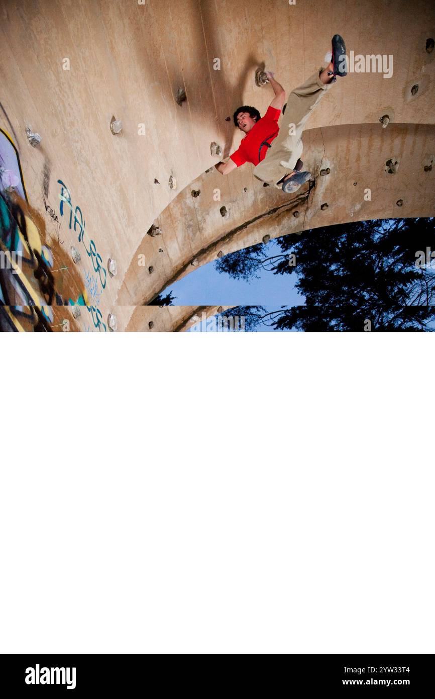 Young climber bouldering below an urban bridge setting surrounded by ...
