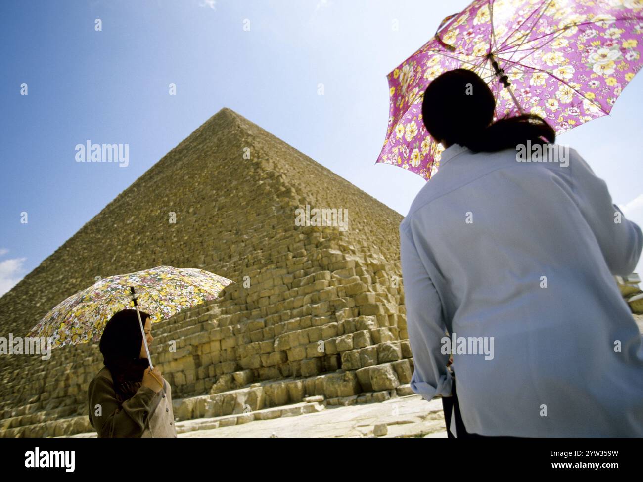 Two tourists contemplating the Great Pyramid of Cheops, Giza plateau ...