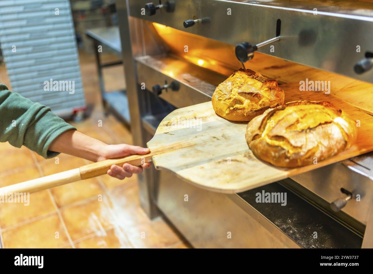 Latin unrecognizable man removing baked artisan bread from oven in a ...