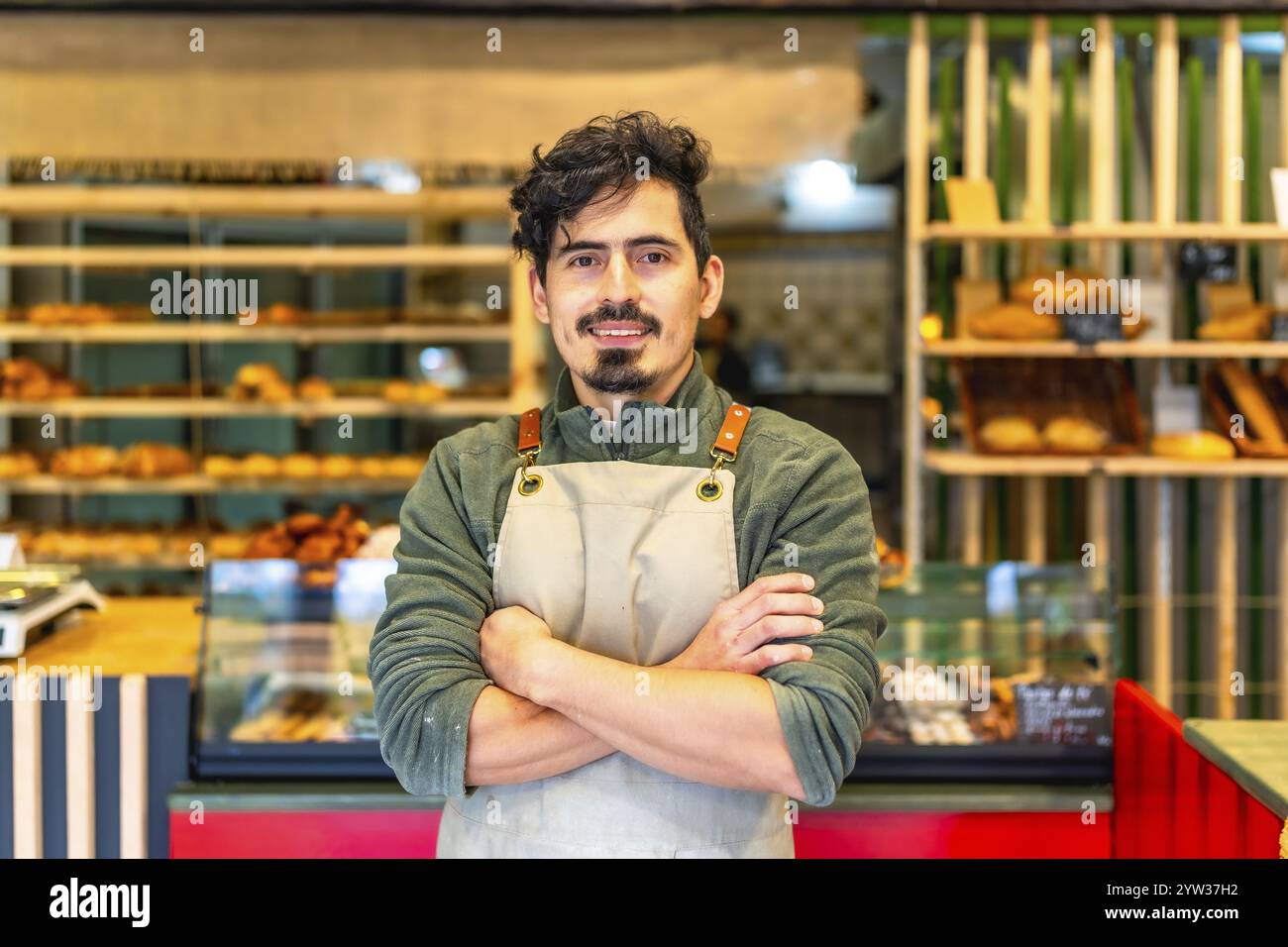 Formal portrait of a latin male young baker standing proud with arms ...