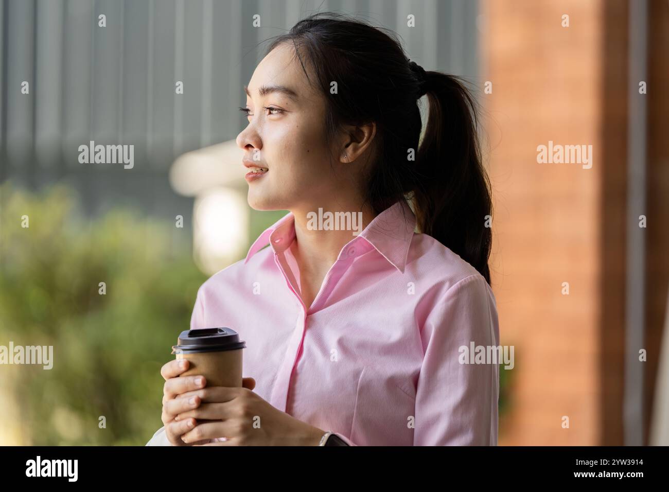 Young woman enjoys coffee while reflecting outdoors in urban setting ...