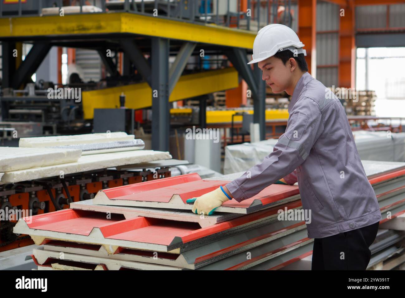 Young asian worker arranging lightweight wall roof sandwich panel for ...