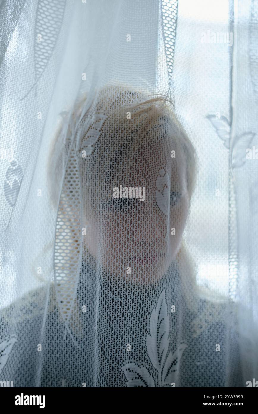 Silhouette of a woman standing behind a sheer lace curtain with ...