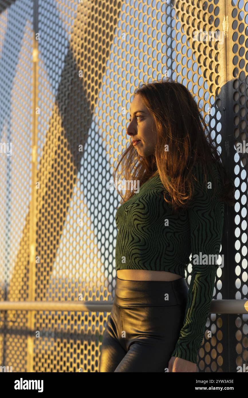 Vertical Side view of a young woman standing on a pedestrian bridge ...