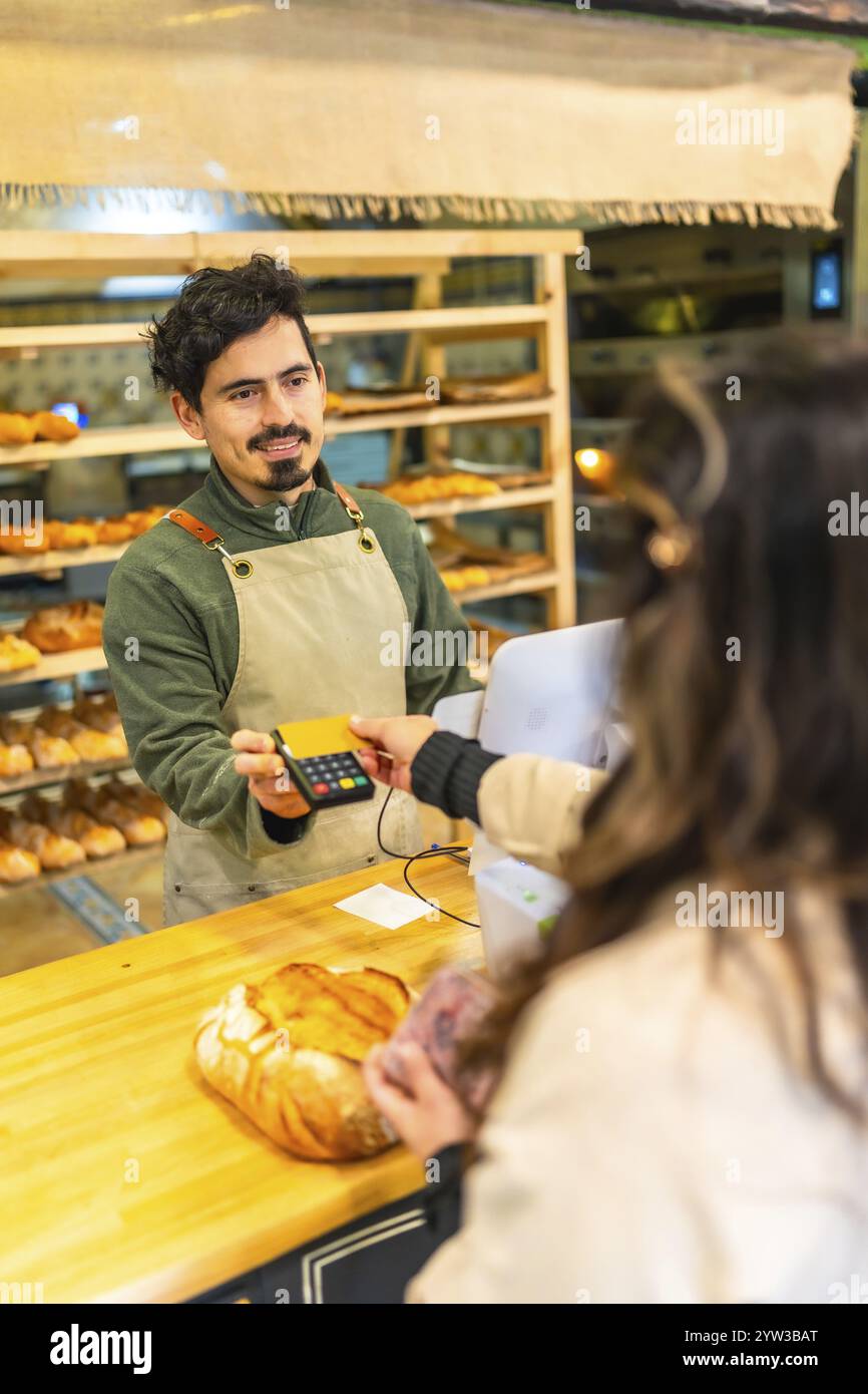 Vertical photo of the rear view of a woman buying bread in a bakery ...