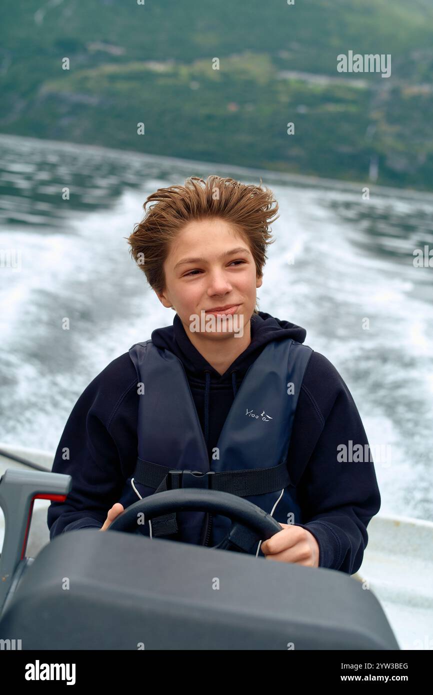 Confident teenager steering a boat with water churned up in the ...