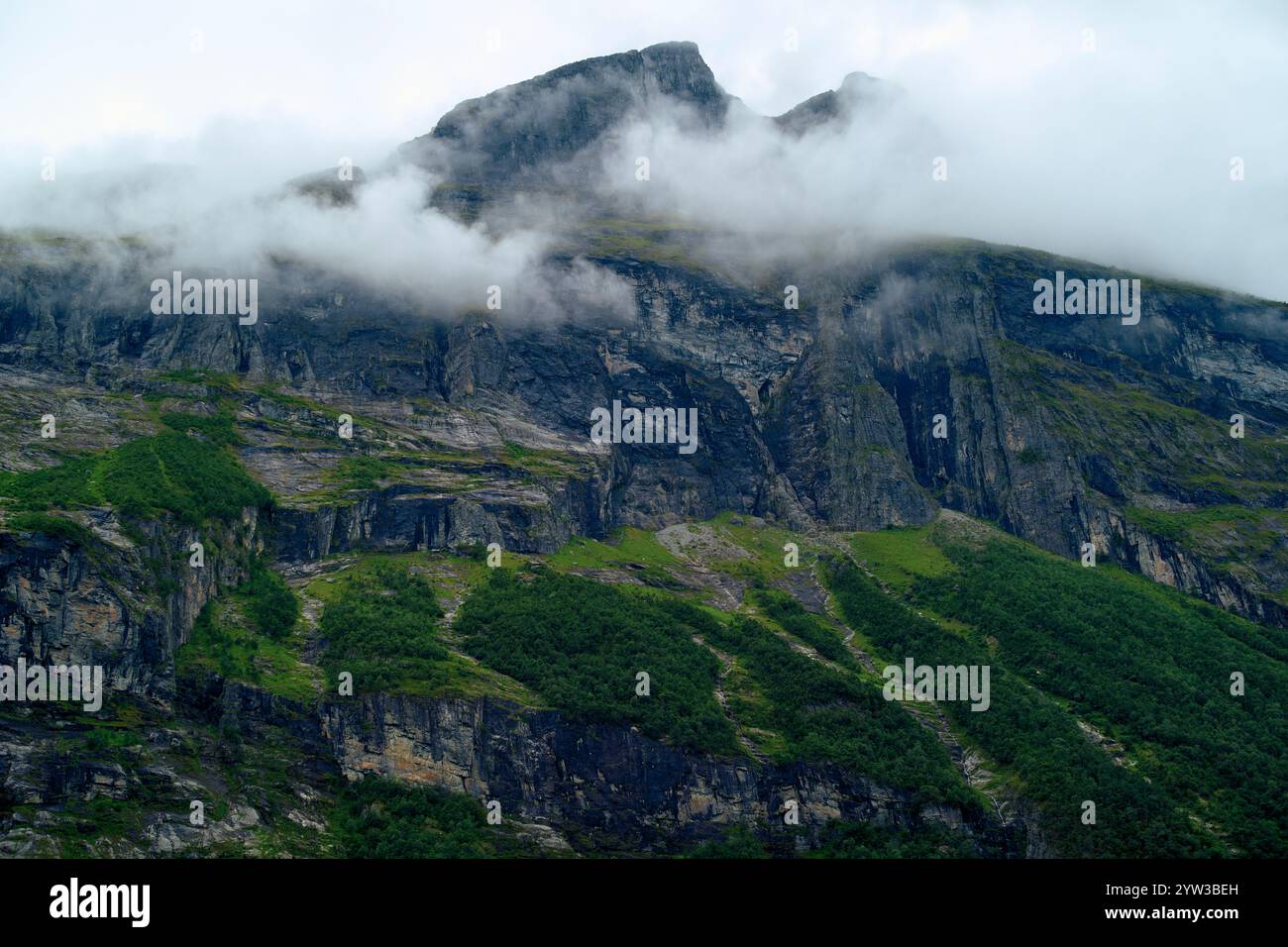 Waterfalls cascade down a rocky mountain face shrouded in mist ...