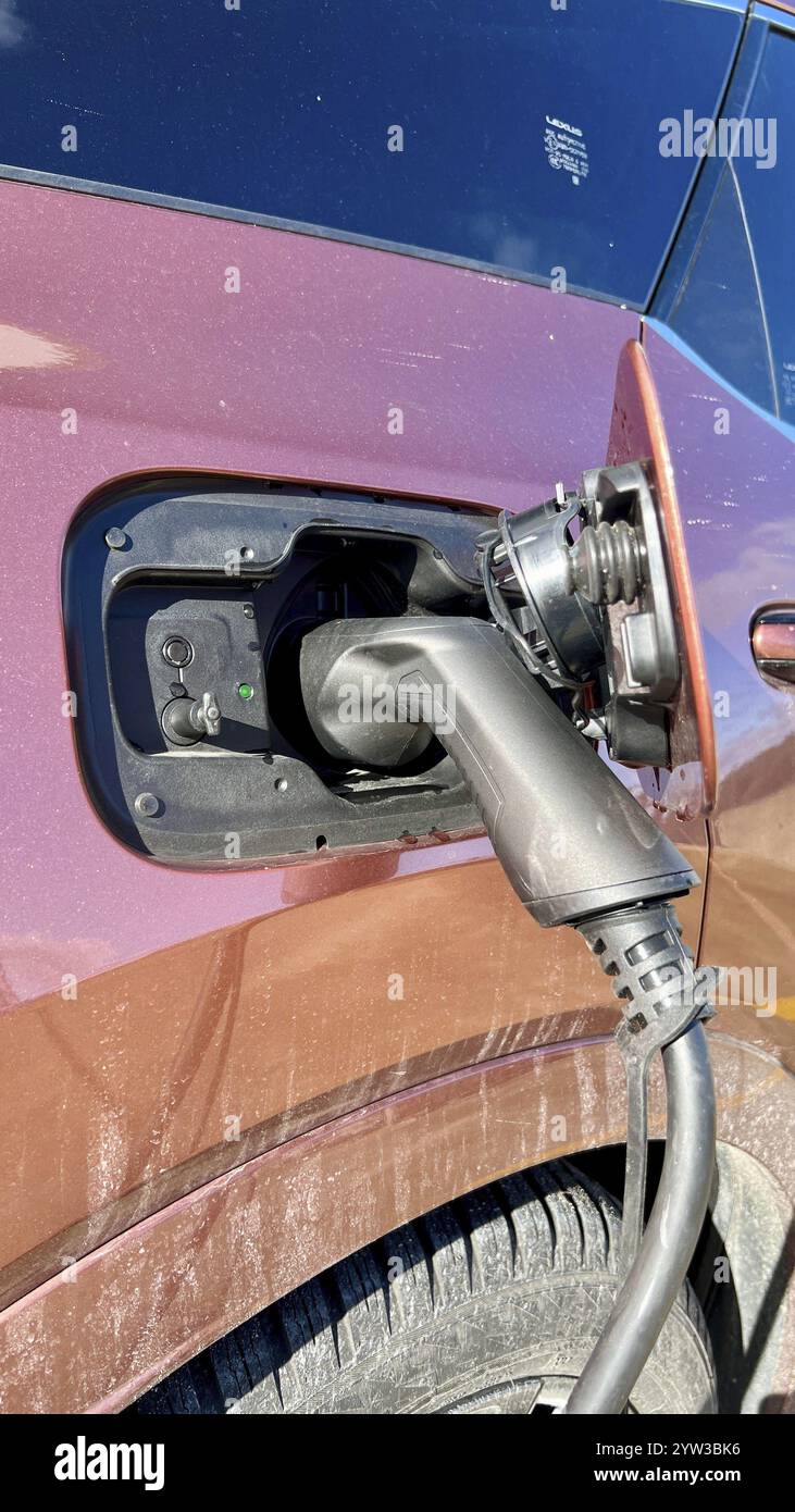 An electric car being charged at an outdoor power station, close-up of ...