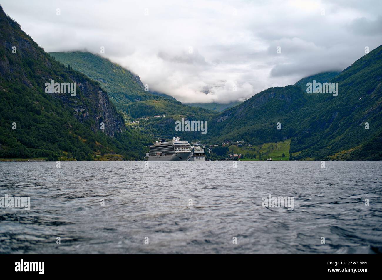 Cruise ships anchored in a fjord with green mountains in the background ...
