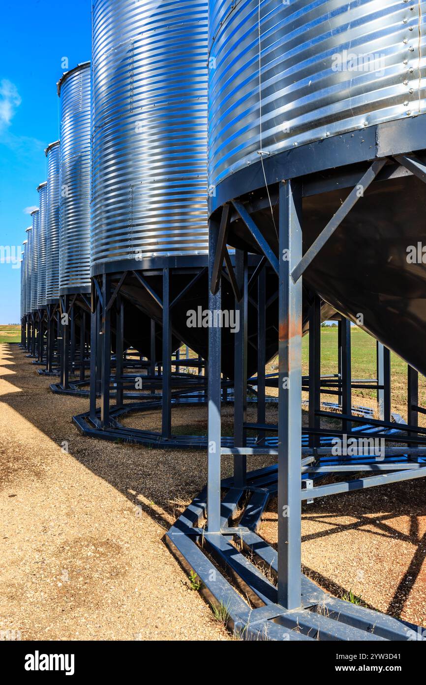 A row of large metal tanks are lined up in a field. The tanks are ...