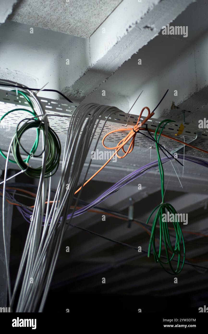 Multicolored network cables hanging from a metal tray on a concrete ...