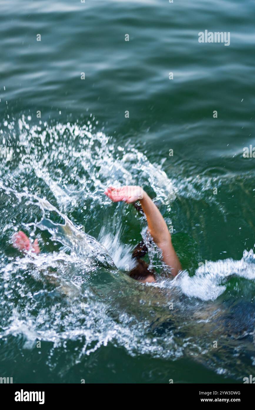 Swimmer captured in vigorous motion creating splashes in open water ...