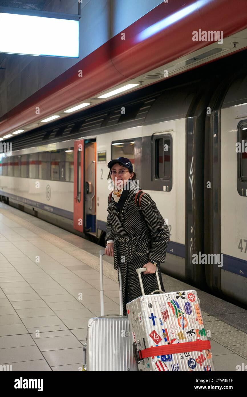 Woman with luggage waiting on a strain platform as a train arrives ...