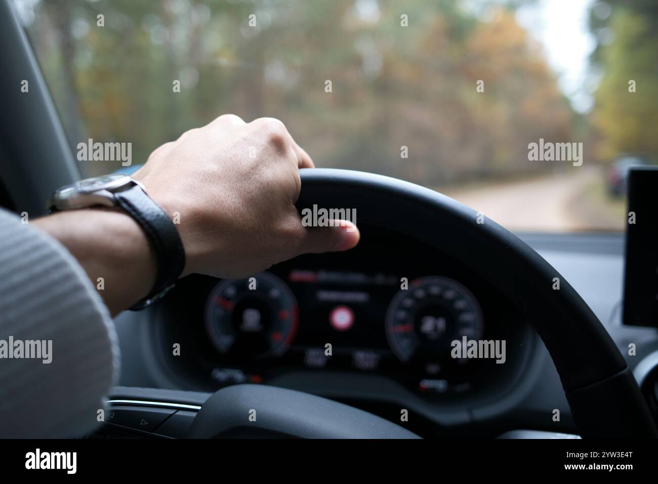 Close-up view of a person's hand on the steering wheel of a car driving ...