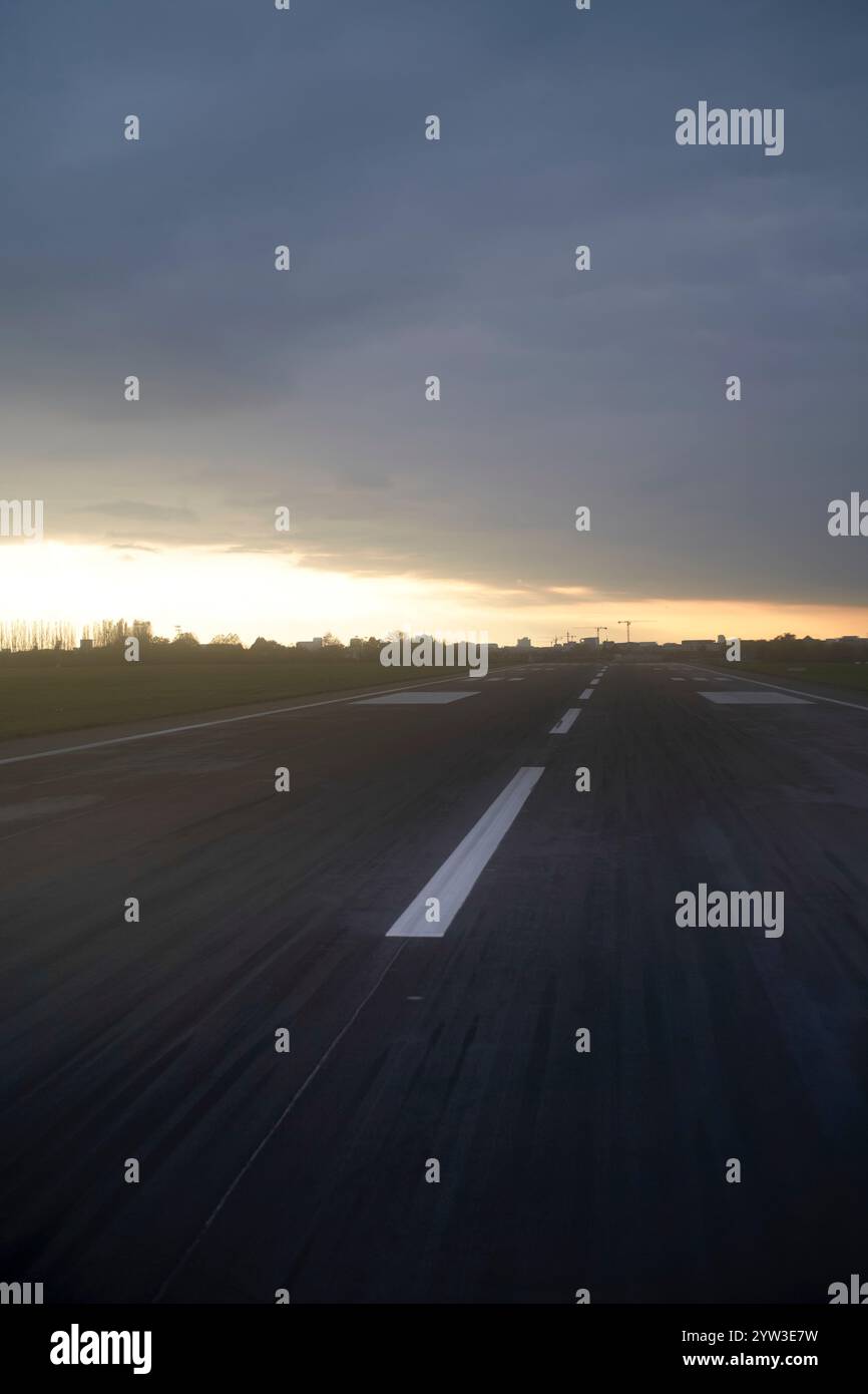 An empty runway during sunrise with clouds in the sky creating a ...