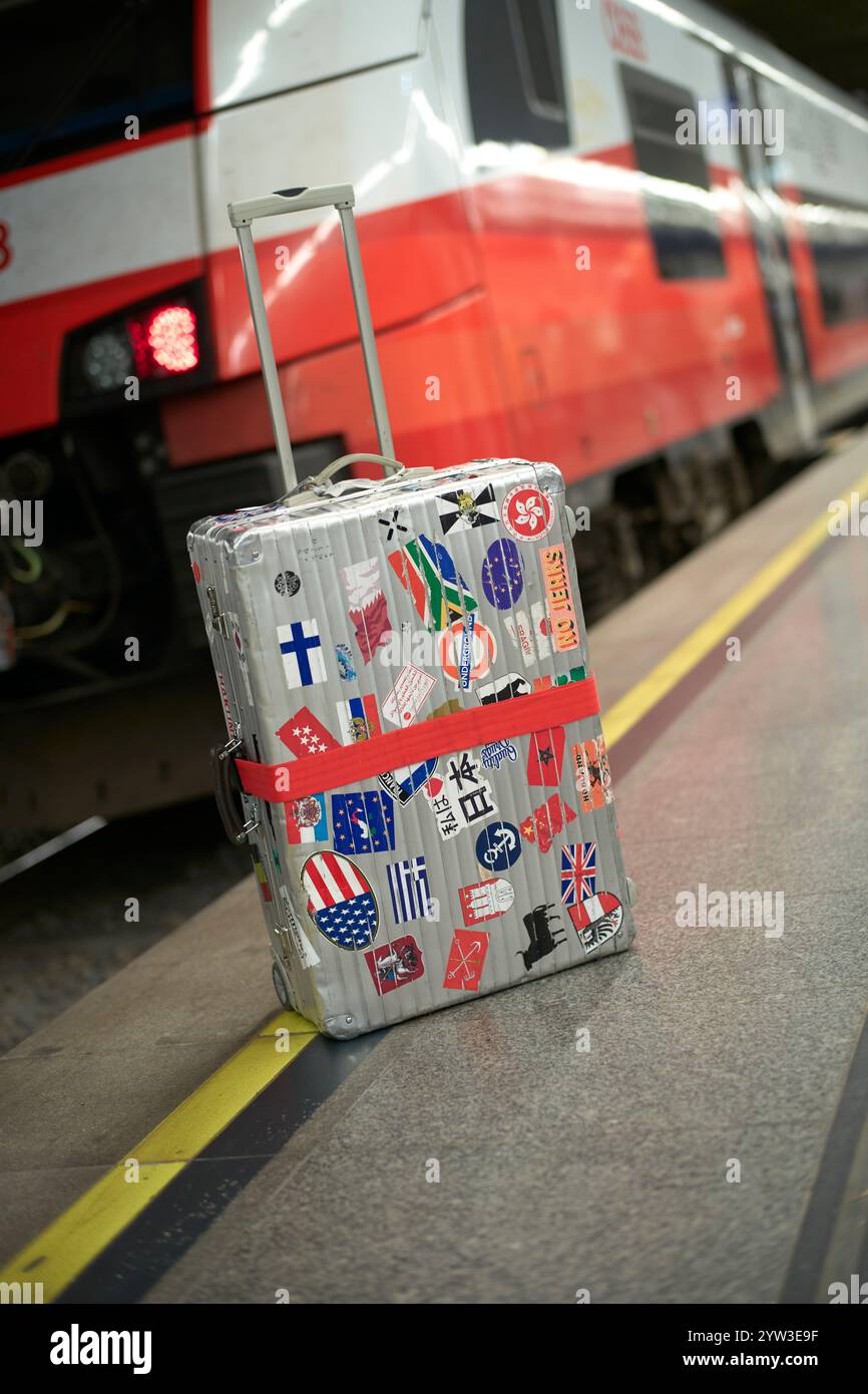 Suitcase covered in various international flags sitting on a train ...