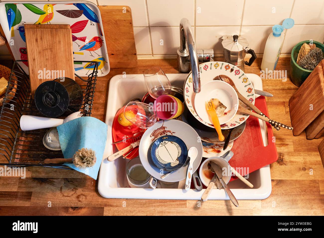 A sink full of dirty dishes and kitchen utensils with colorful designs ...
