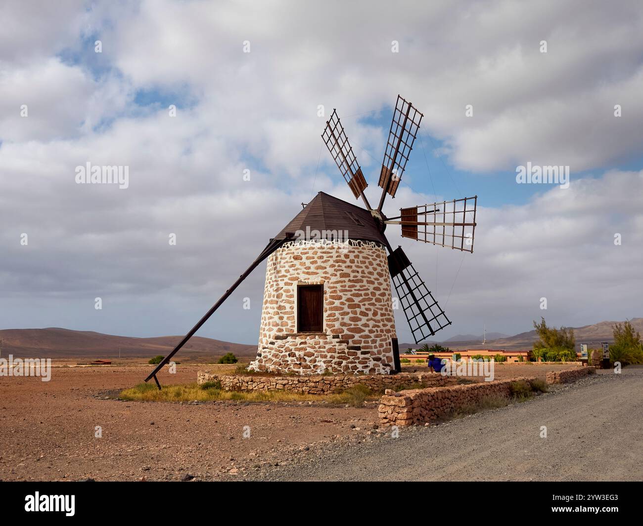 Traditional stone windmill with wooden blades under a cloudy sky, next ...