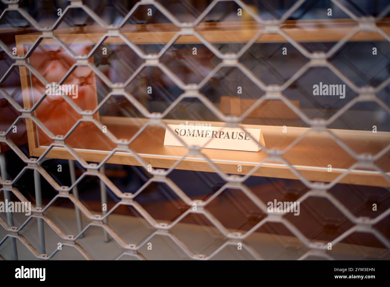 A sign reading SOMMERPAUSE summer break is visible behind a metal grid ...