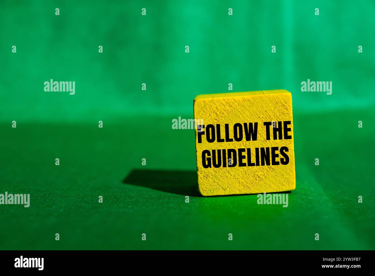 Follow the guidelines message written on yellow wooden cube with green ...