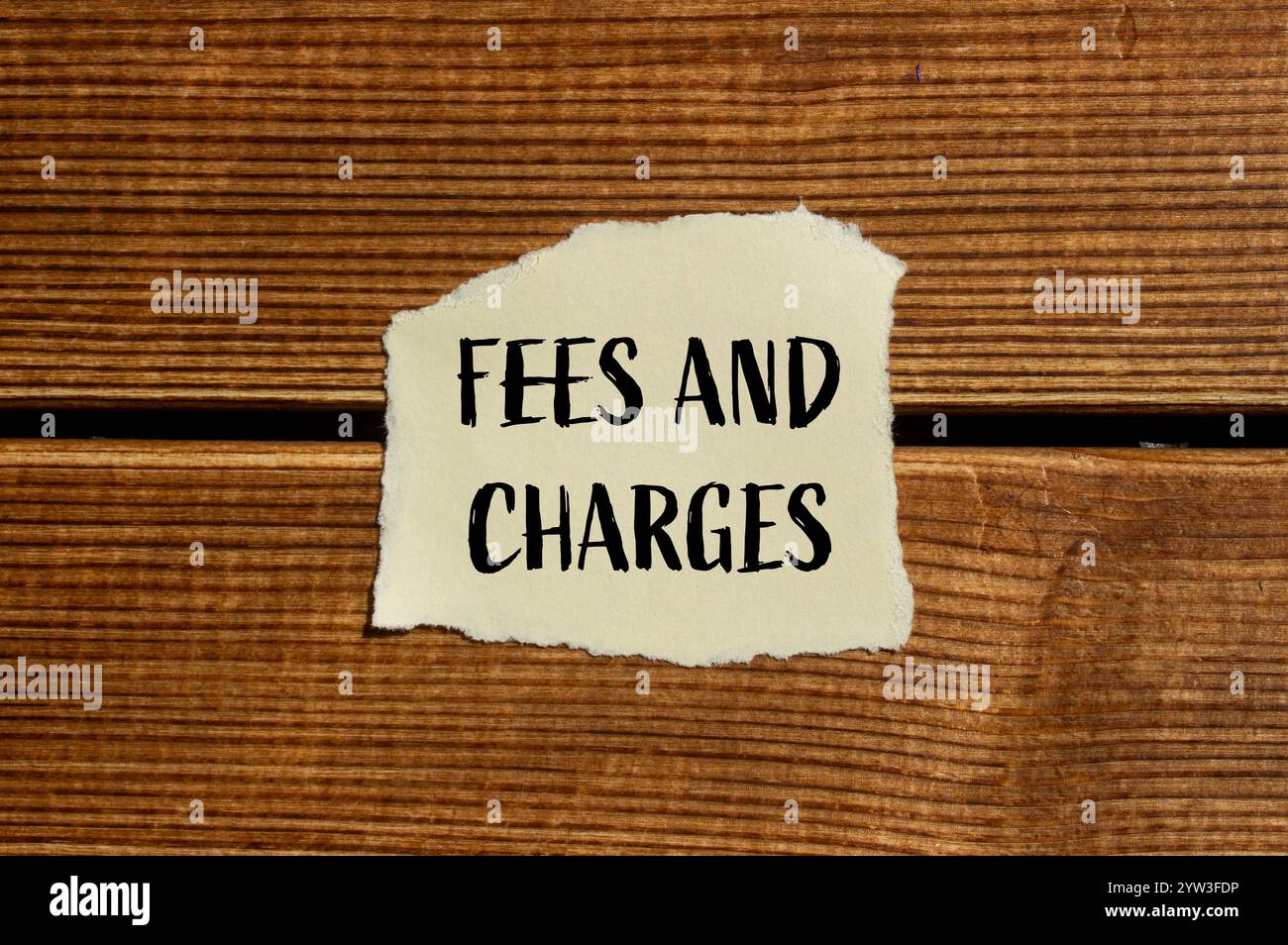 Fees and charges message written on ripped torn paper with wooden ...