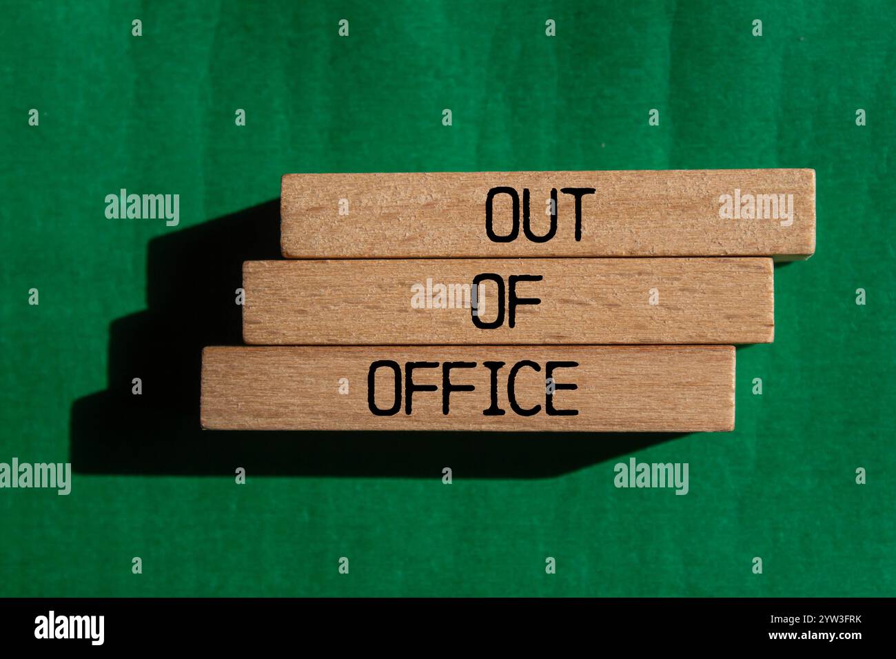 Out of office message written on wooden blocks with green background ...