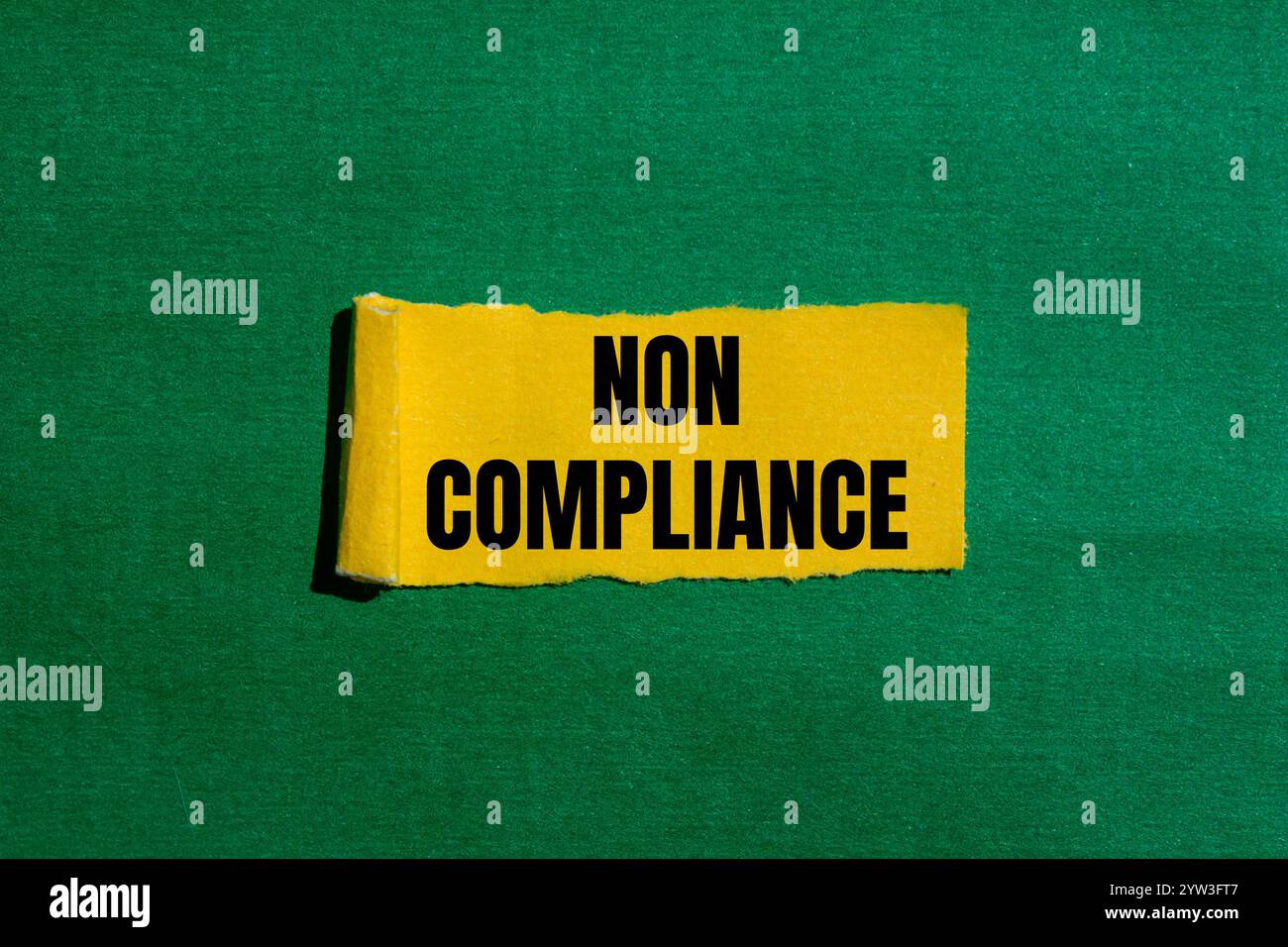 Non compliance message written on ripped torn yellow paper piece with green background ...