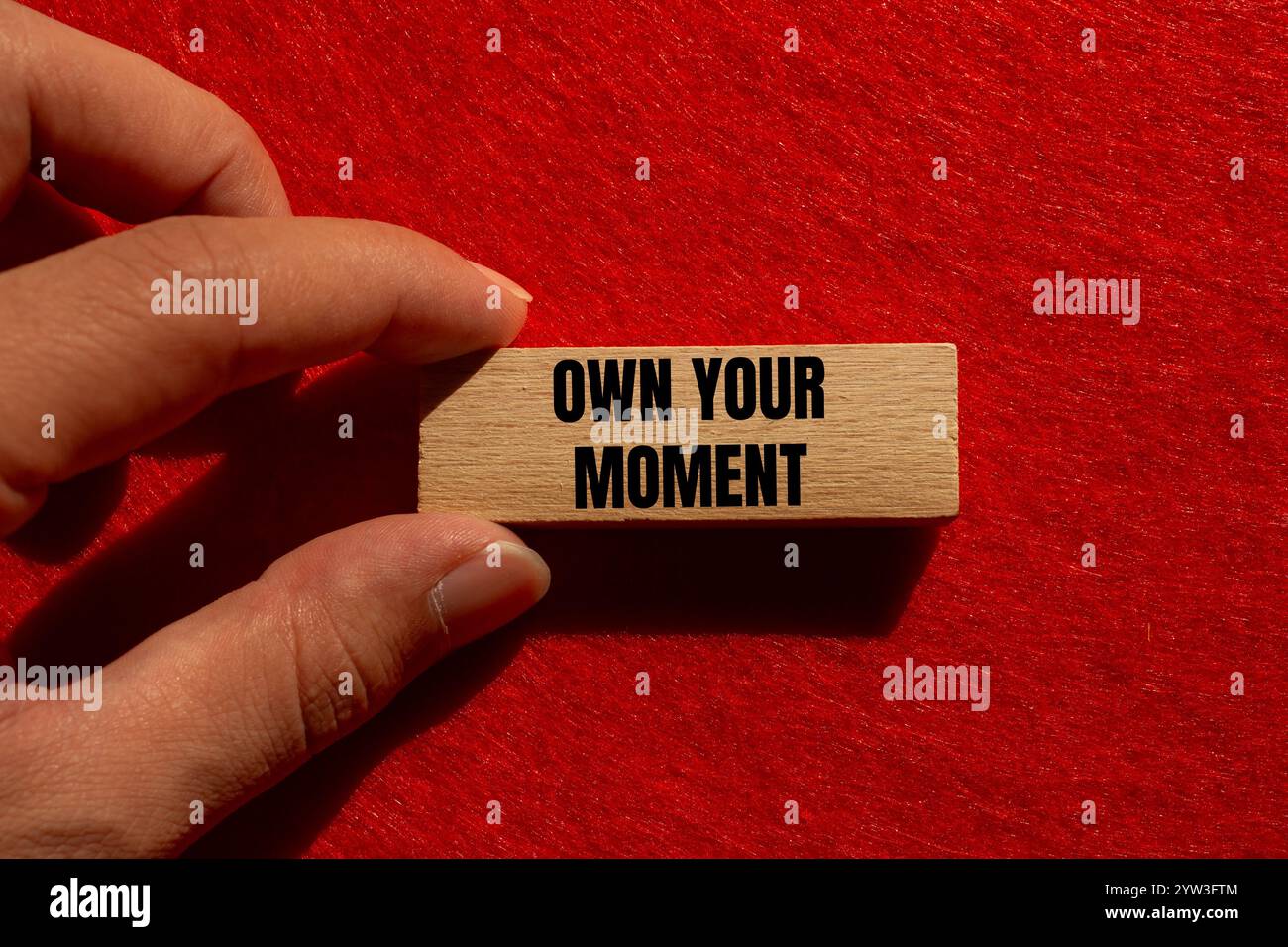 Own your moment message written on wooden block with red background ...